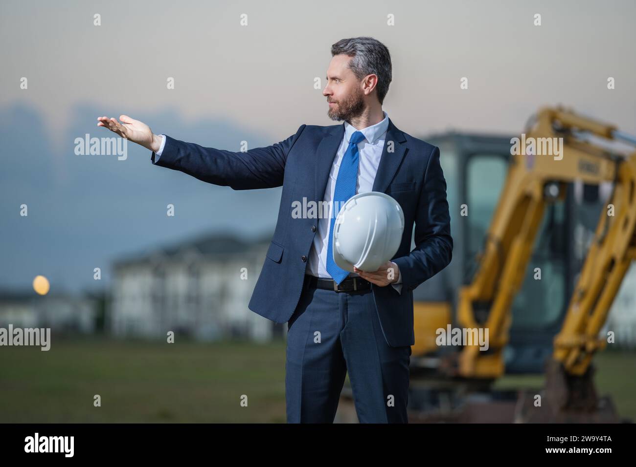 Architect at a construction site. Architect man in helmet and suit at ...