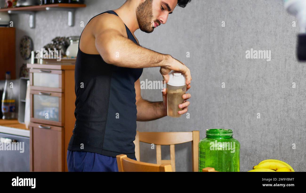 Young athletic man drinking a healthy smoothie drink or a protein shake ...