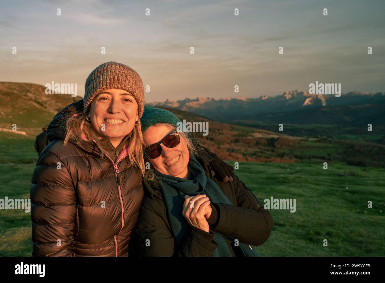 portrait of two friends hugging watching the sunset surrounded by ...