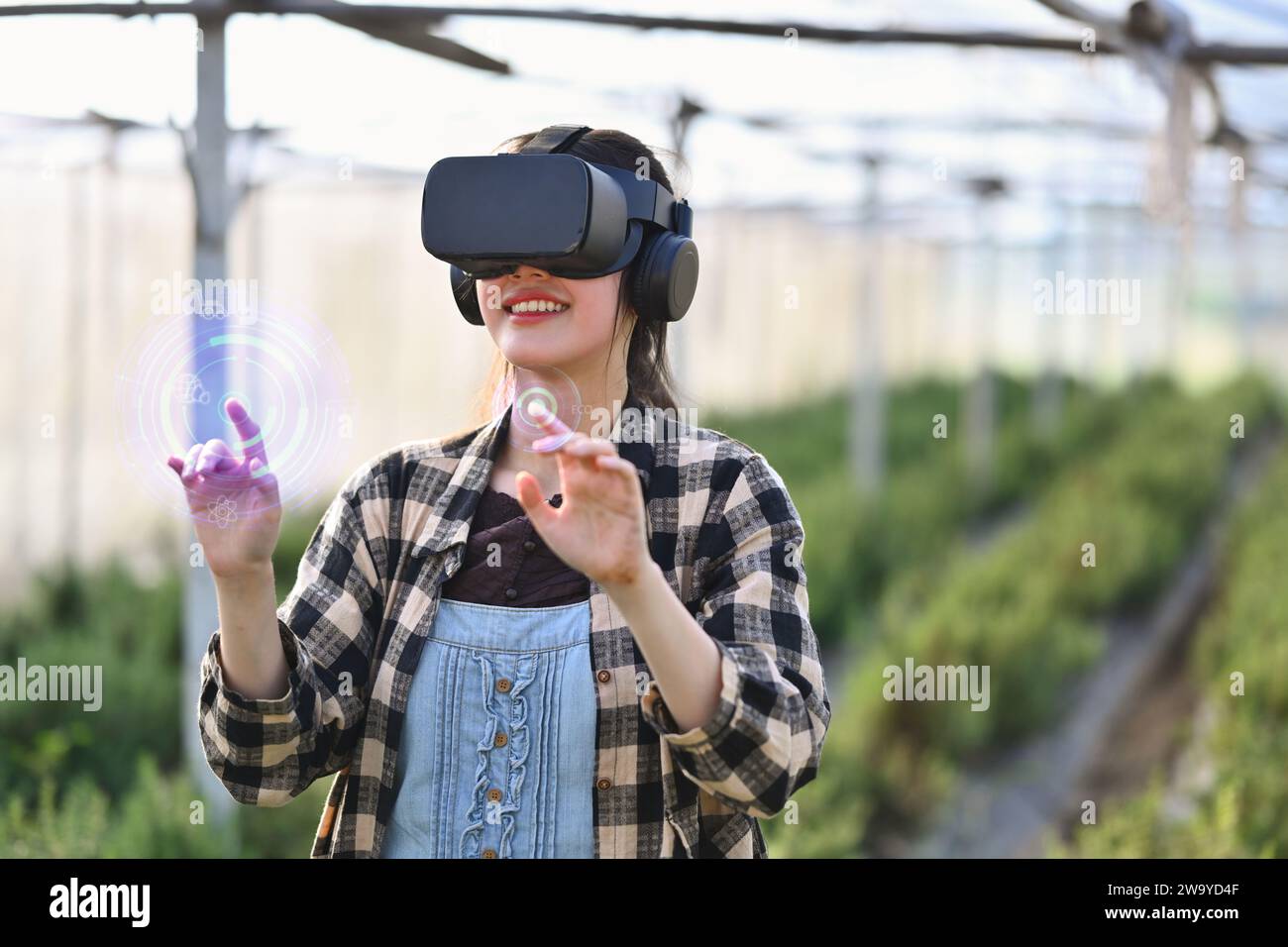 Farmer wearing VR headset for controlling process in greenhouse ...
