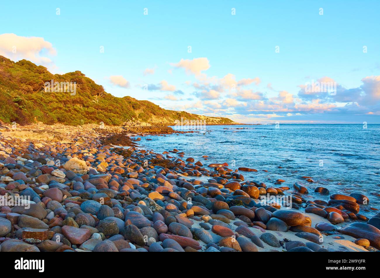 Sunrise illuminating smooth granite stones on the beach and coastal ...