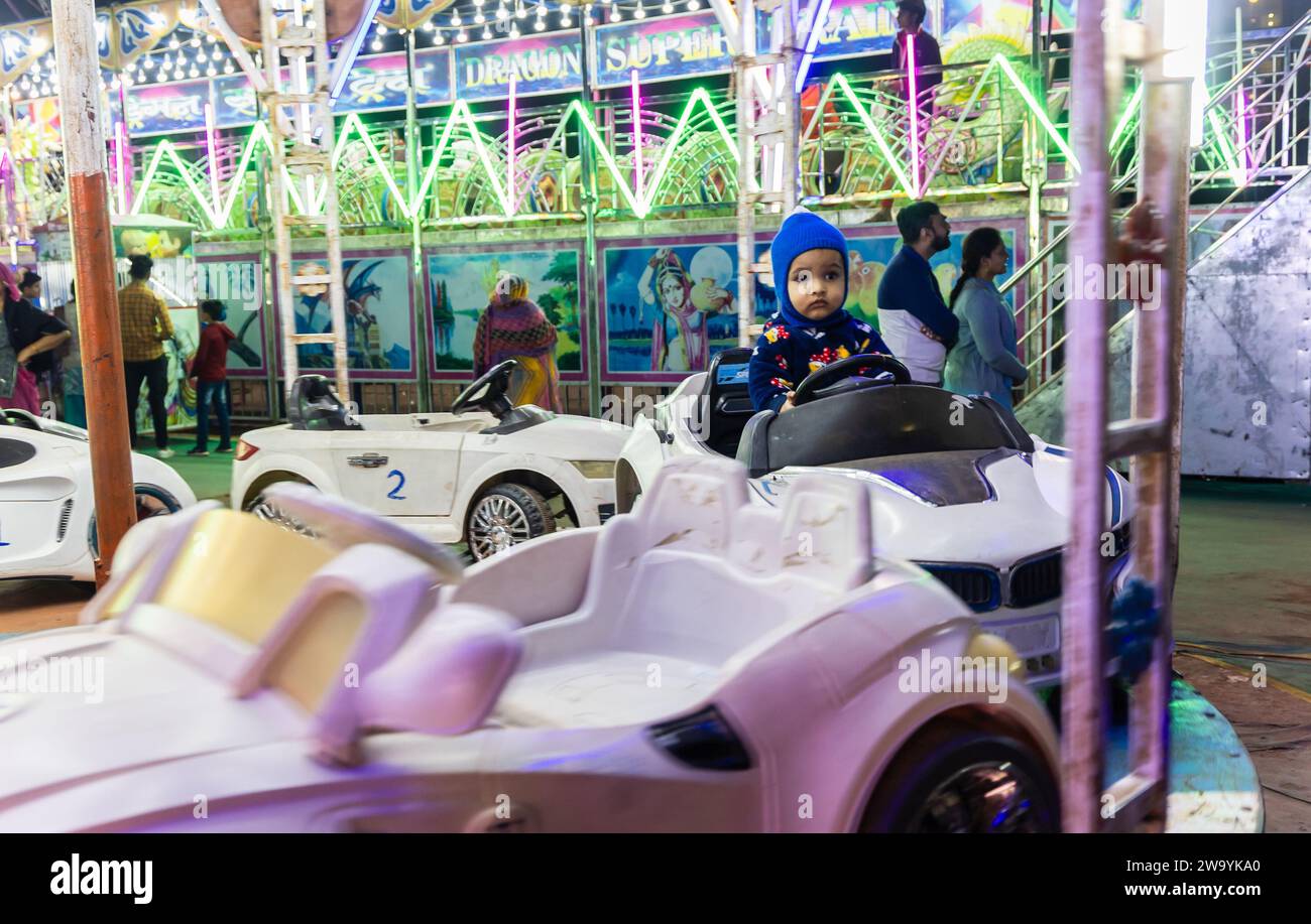 kid enjoying children merry go round swing at night at city fair ground ...