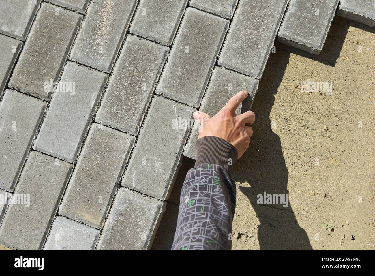 A worker lays paving slabs on the sand at a construction site Stock ...