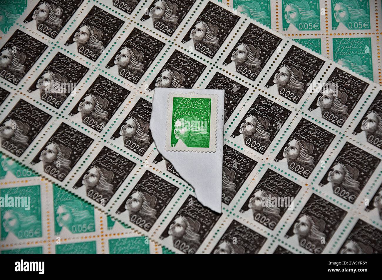 In this photo illustration, a green stamp is placed on a sheet of black ...