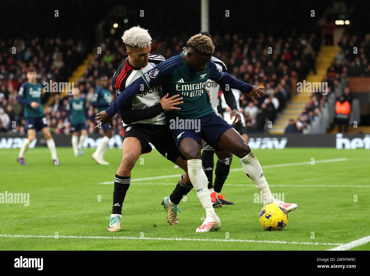 Fulham's Antonee Robinson (left) and Arsenal's Bukayo Saka battle for the ball during the ...
