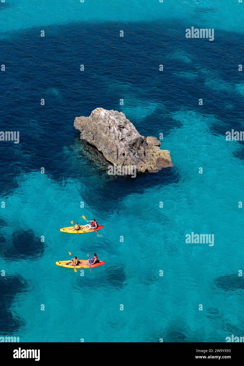 A family kayaking in clear blue sea Cala Macarella, menorca minorca ...