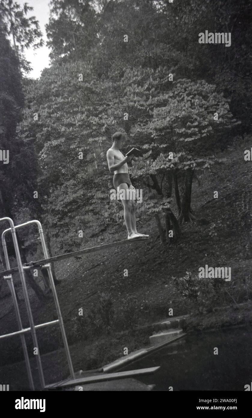 1950s, historical, a male swimmer standing on a diving board, reading ...