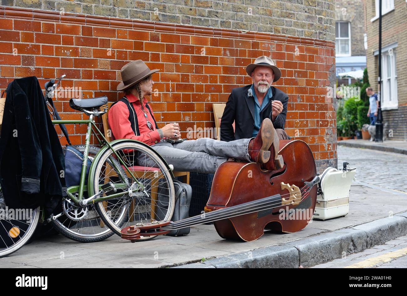 Two musicians smoking relaxing at Colombia Road, London with cycle and ...