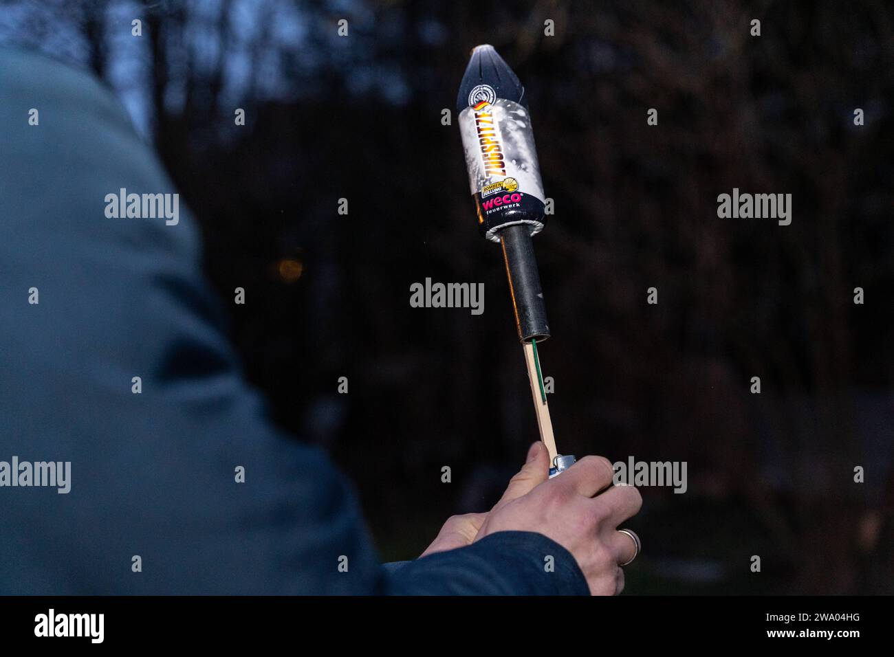 Kammlach, Bavaria, Germany - December 31, 2023: Man lights a rocket ...