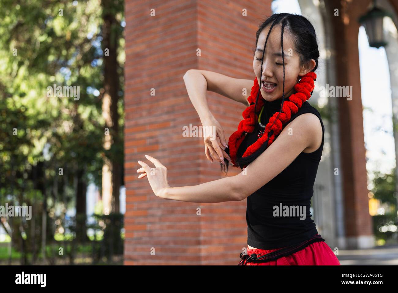 Portrait of young asian woman dancing with her arms in the street from ...