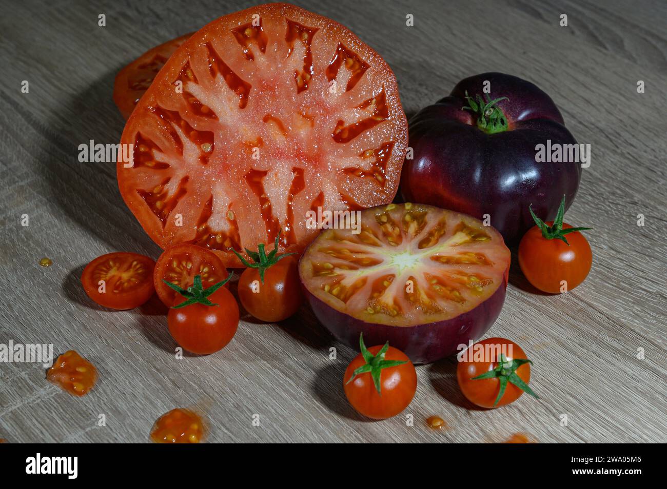 A group of tomatoes, one large pink cut in half facing the photo ...