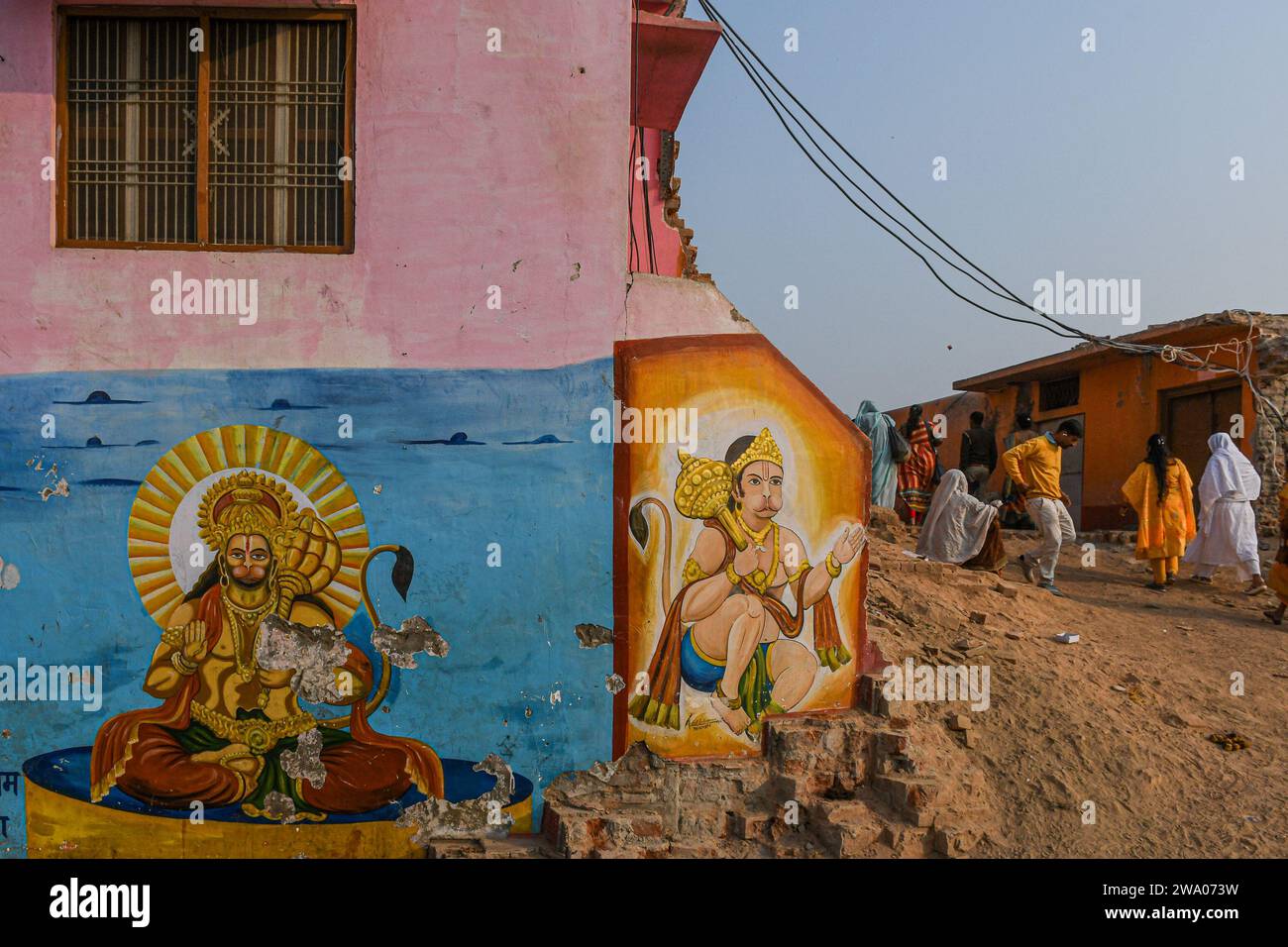 Ayodhya, India. 26th Dec, 2023. People walk past murals of Hindu gods ...