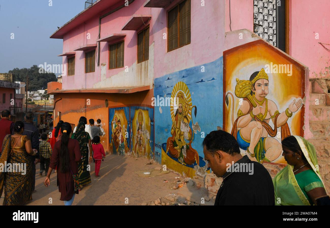 Ayodhya, India. 26th Dec, 2023. People walk past murals of Hindu gods ...