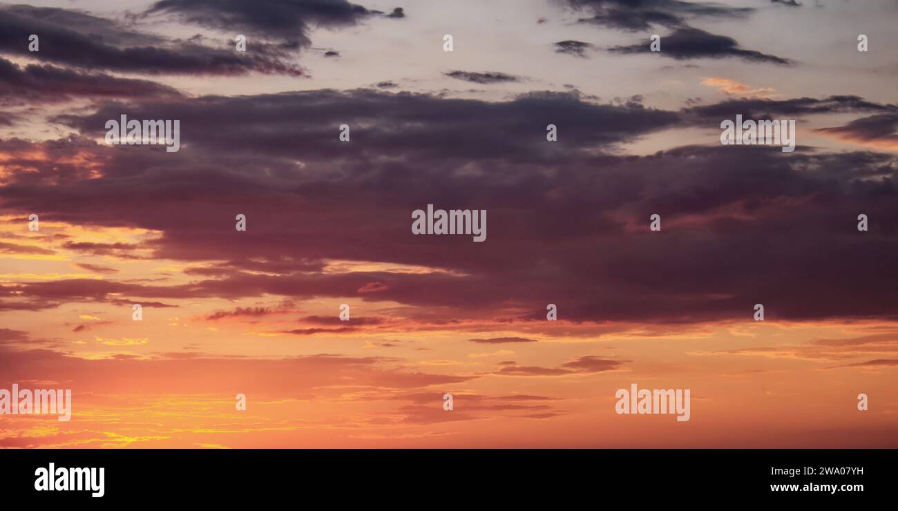 The sun setting behind scattered clouds in a colorful sky Stock Photo ...