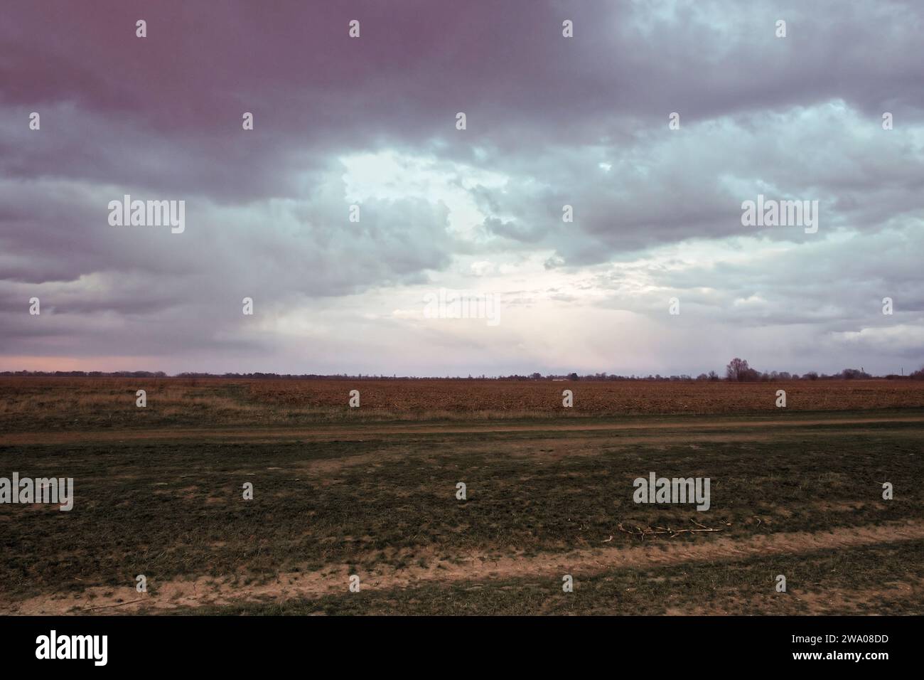 An open field with dark clouds gathering above Stock Photo - Alamy