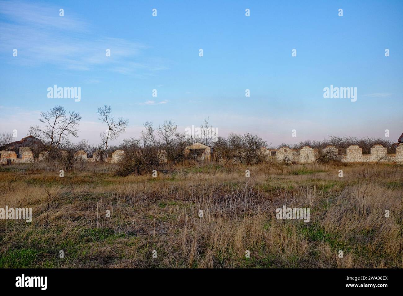 A crumbling brick wall, remnants of a larger structure, stands in an ...