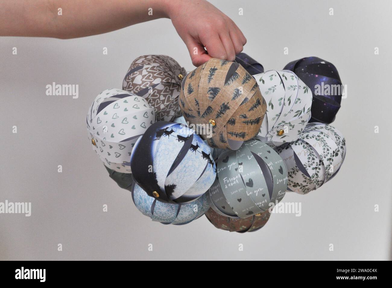 A collection of handmade paper baubles being held together set against ...