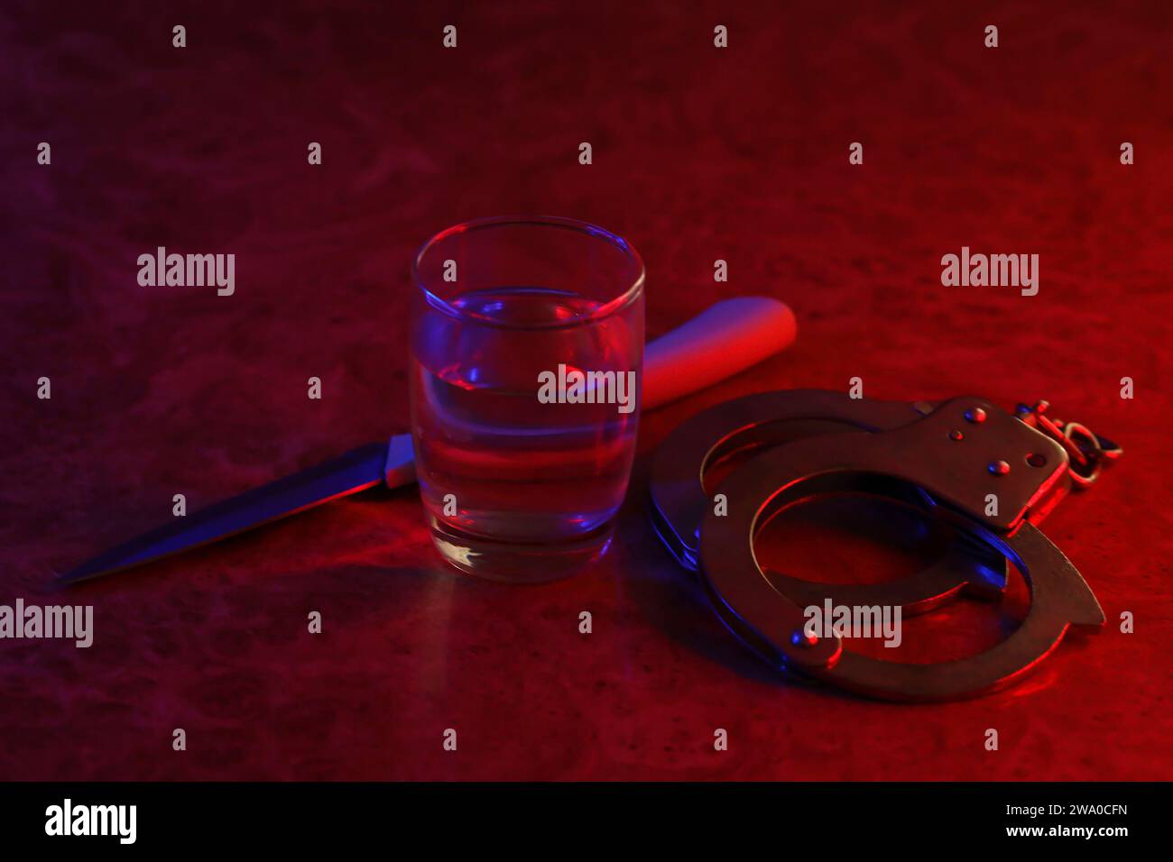 Glass with vodka alcohol drink, knife and handcuffs. Concept of ...