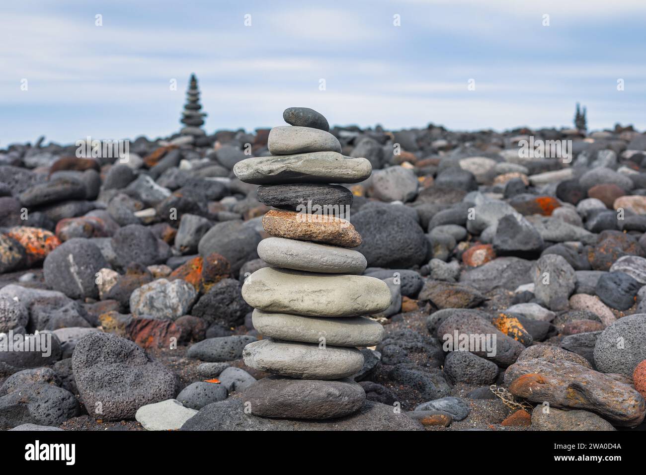 Pebble beach with pyramid of stones . Stacked stones on the ocean coast ...