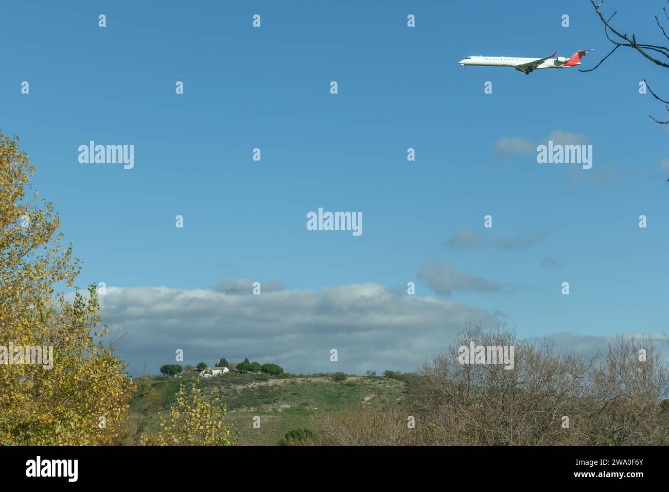 A countryside landscape with houses on a hill and a passenger plane ...