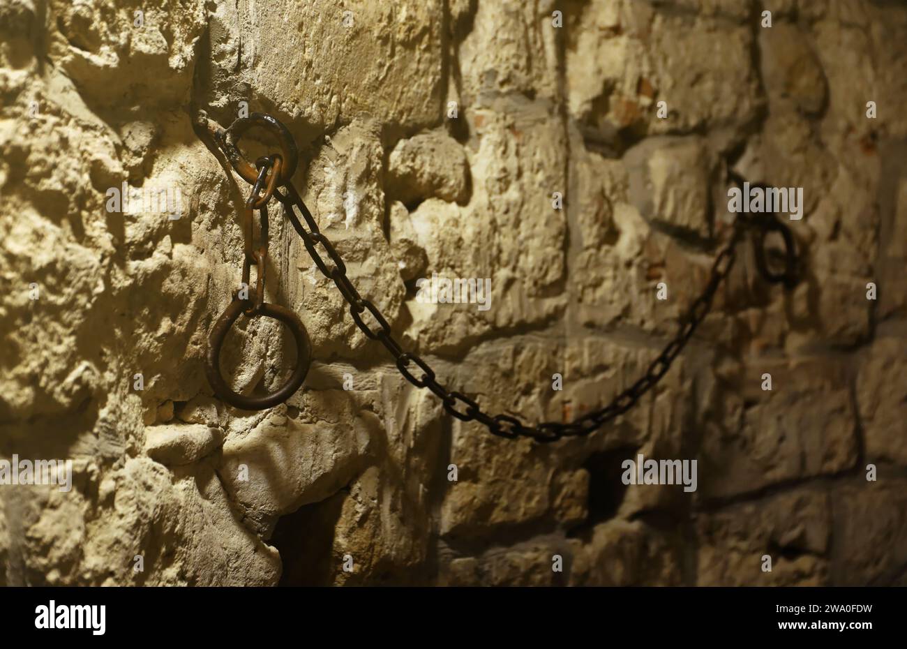 Slavery and bondage strong steel old shackles on stone wall in castle ...
