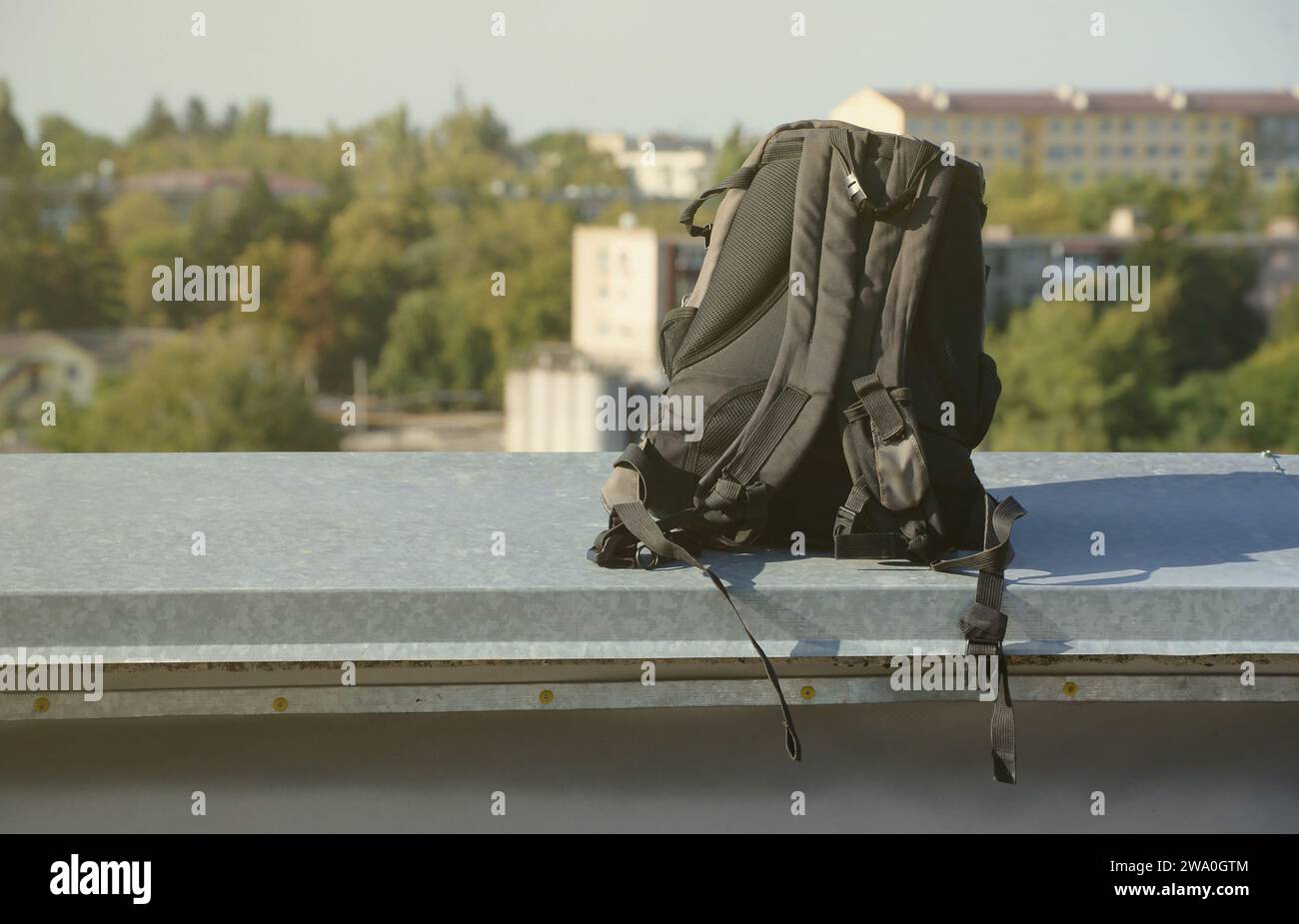 Black backpack lies on metal border of residental multistorey building ...