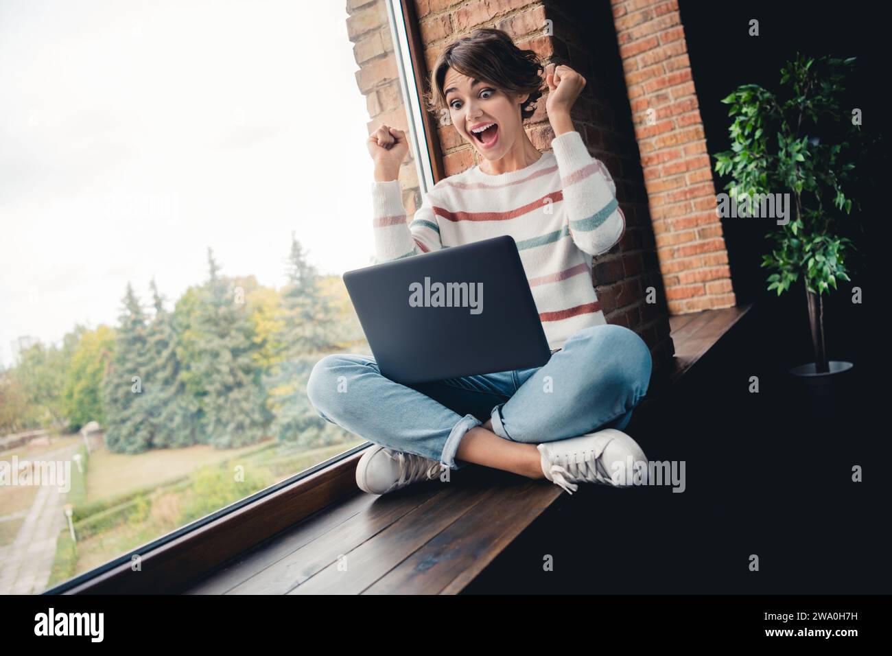 Full body photo of delighted lady sit window sill use laptop raise ...