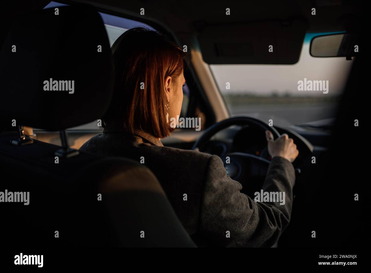 Young beautiful smiling woman taxi driver in a jacket sits behind the ...