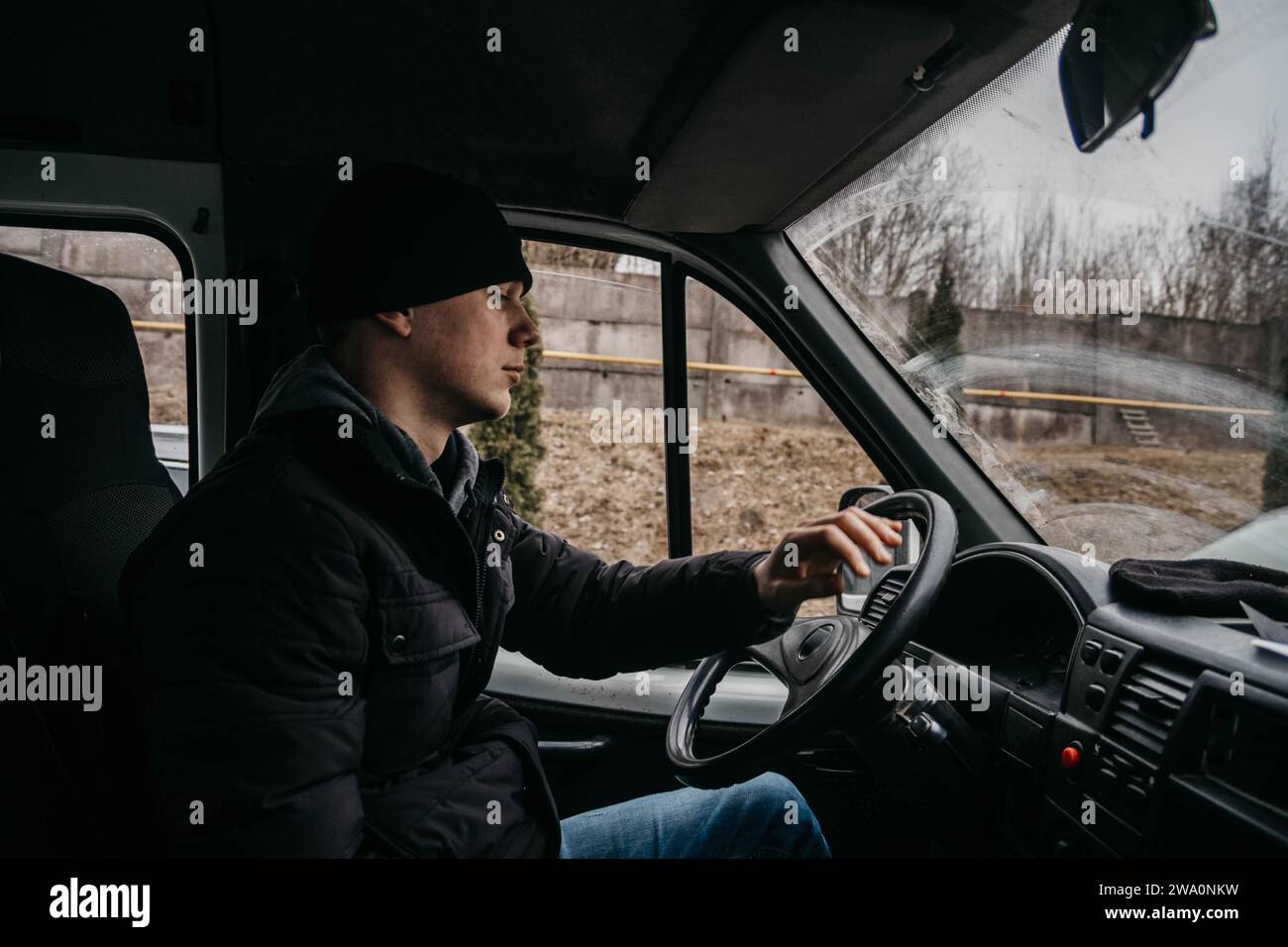 Young truck driver sitting behind the wheel, going to order for cargo ...