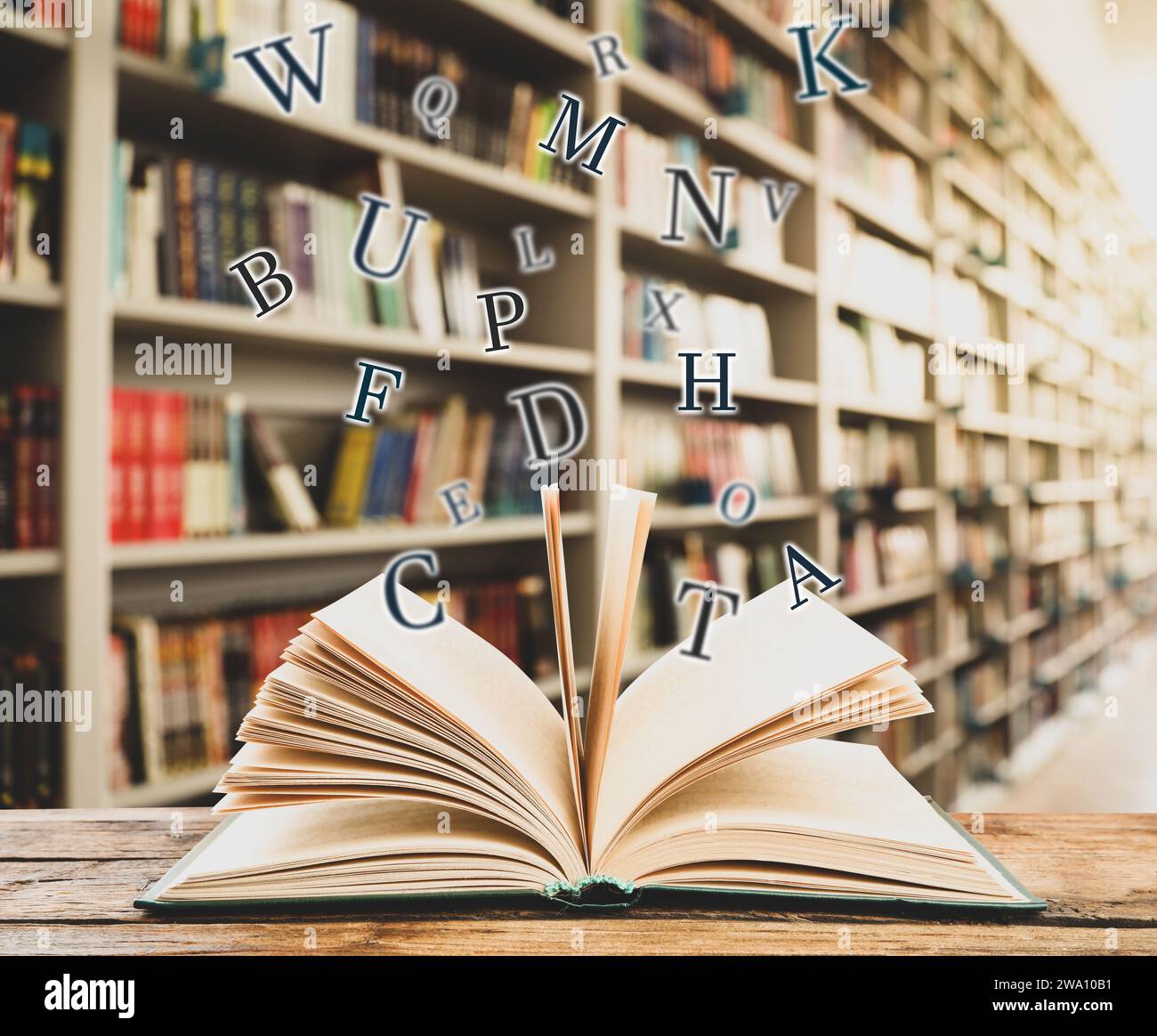Open book with letters flying out of it in library Stock Photo - Alamy