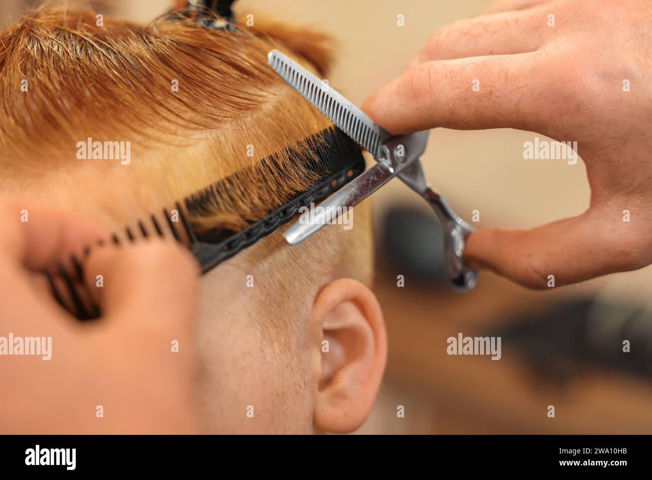 Professional hairdresser cutting boy's hair in beauty salon, closeup ...