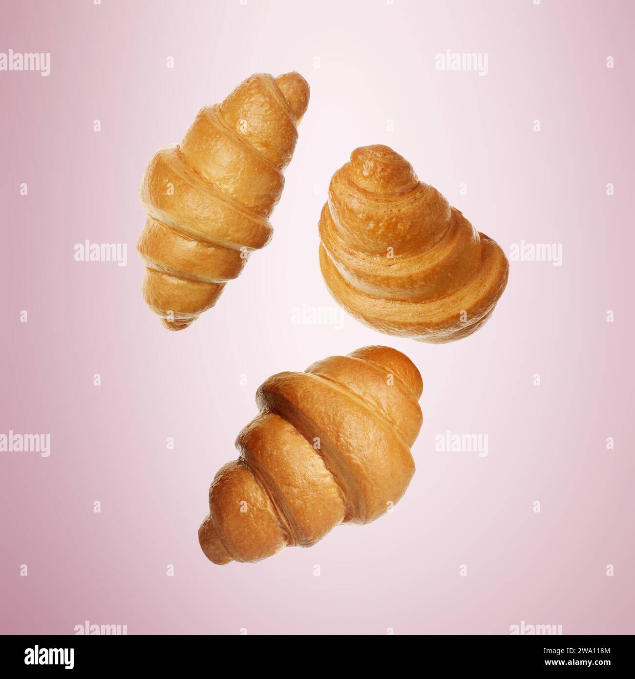 Golden croissants falling on pink gradient background Stock Photo - Alamy