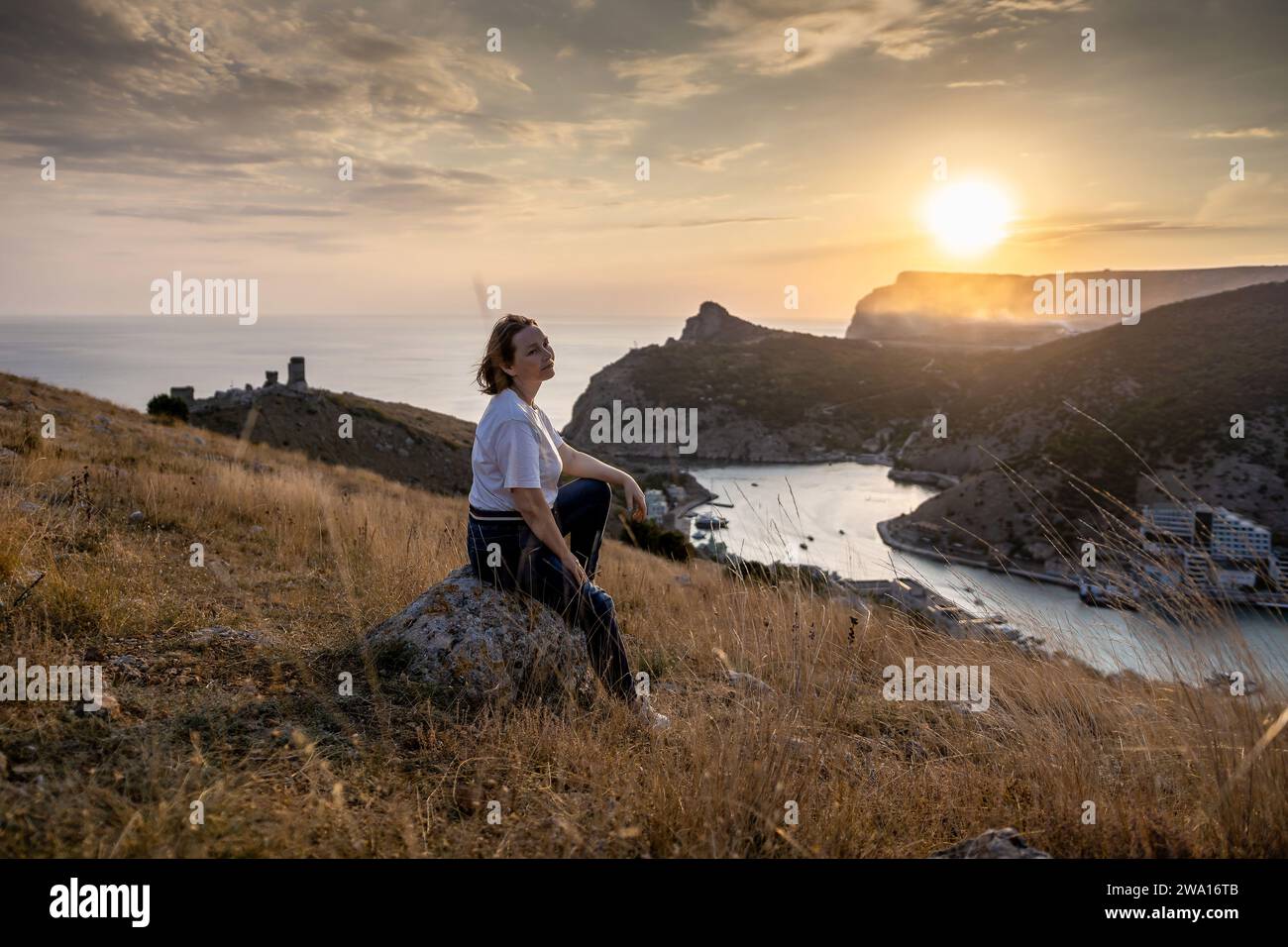 Happy woman on sunset in mountains. Woman siting with her back on the ...