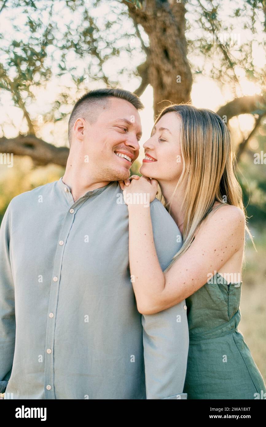 Young woman put her hands and chin on the shoulder of man who turned ...