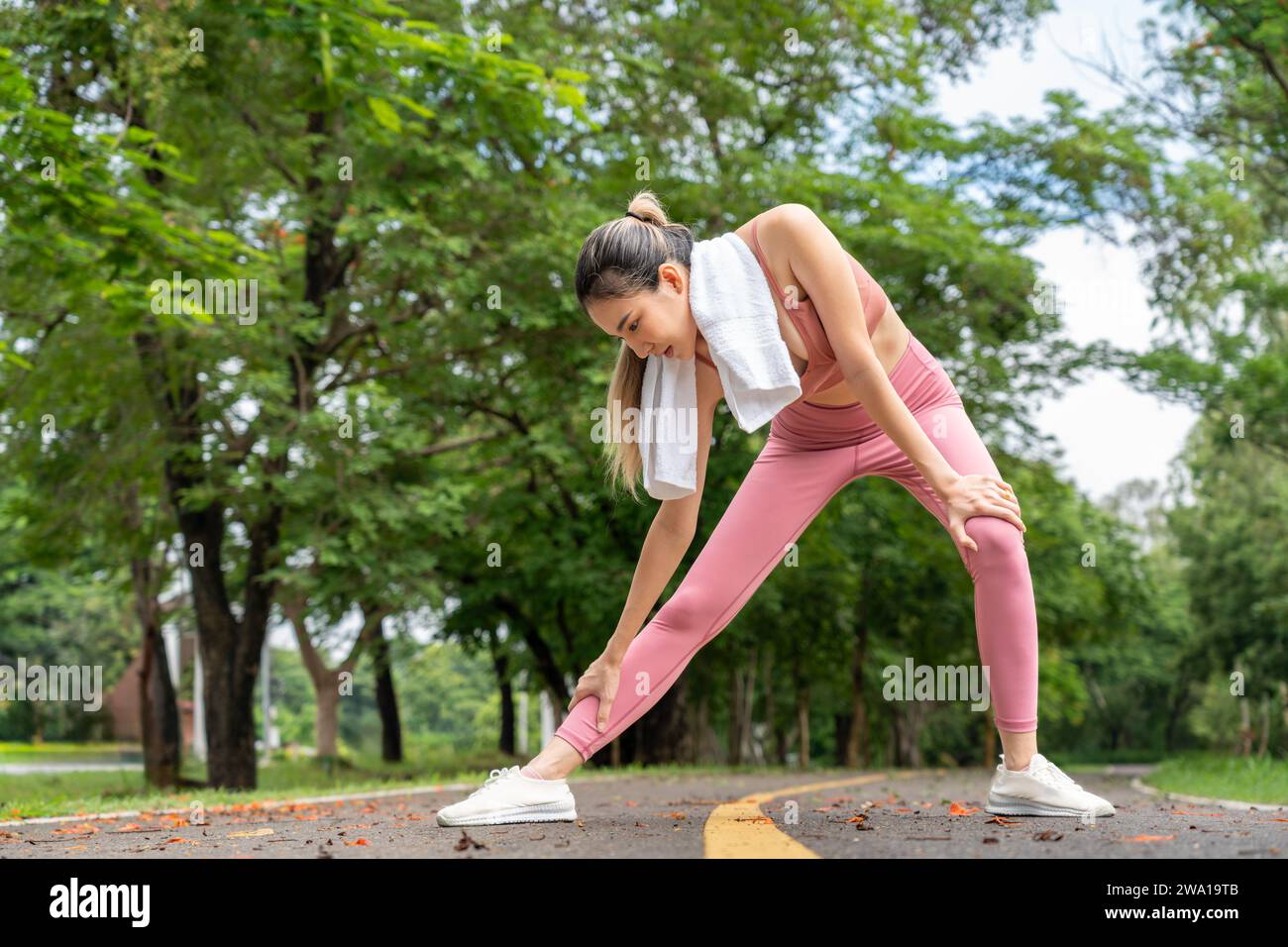 Young attractive Asian woman stretching her arms and legs before her morning exercise run at a ...