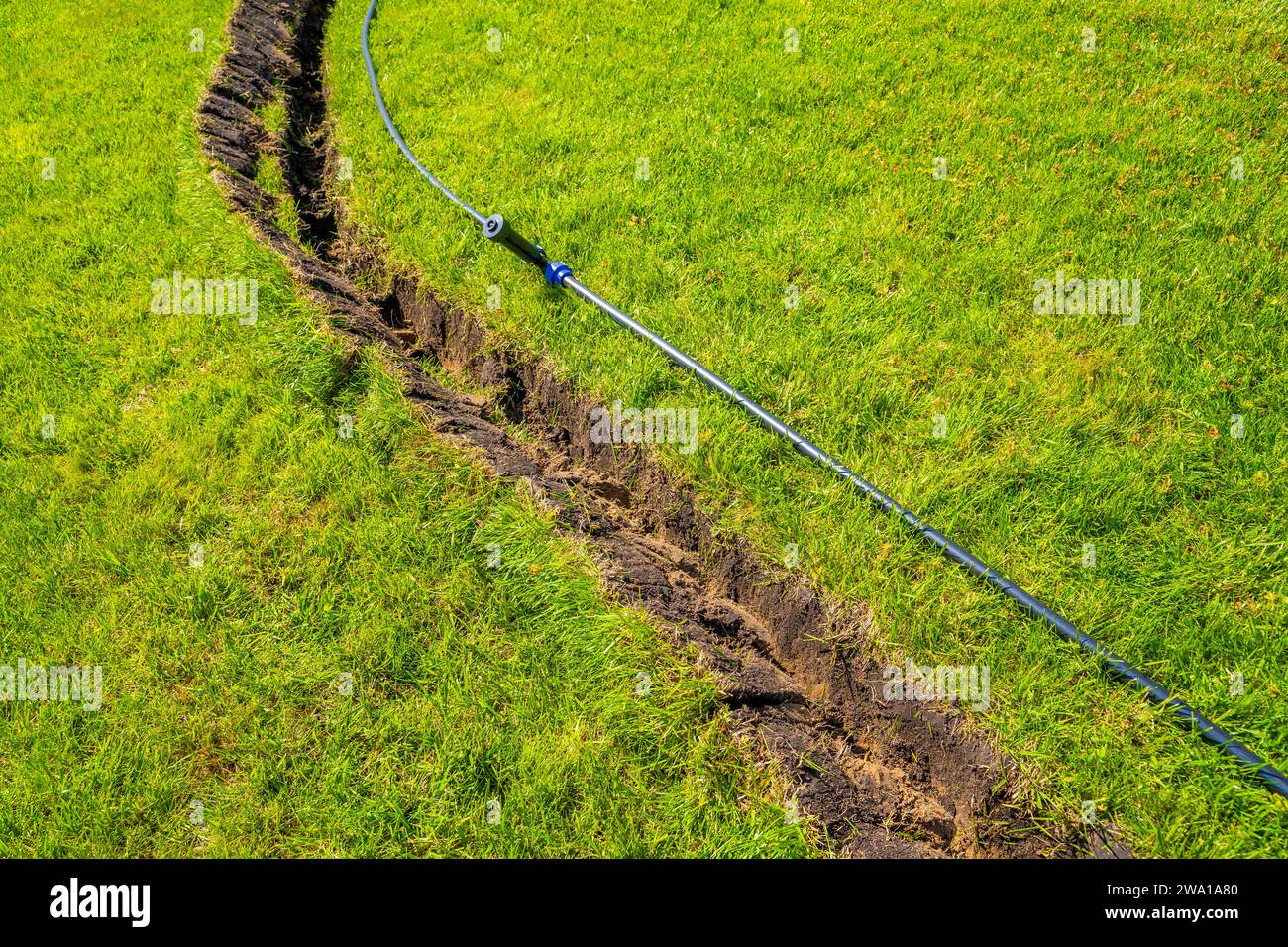 A ditch dug in the lawn for laying pipes and installing irrigation ...