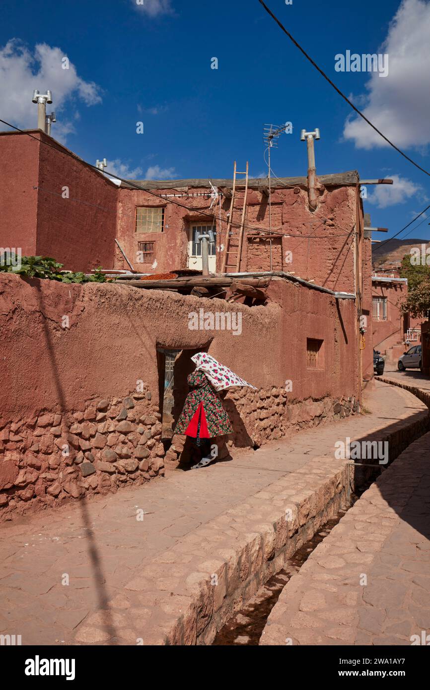 Local woman in traditional clothing steps into the doorway of a house ...