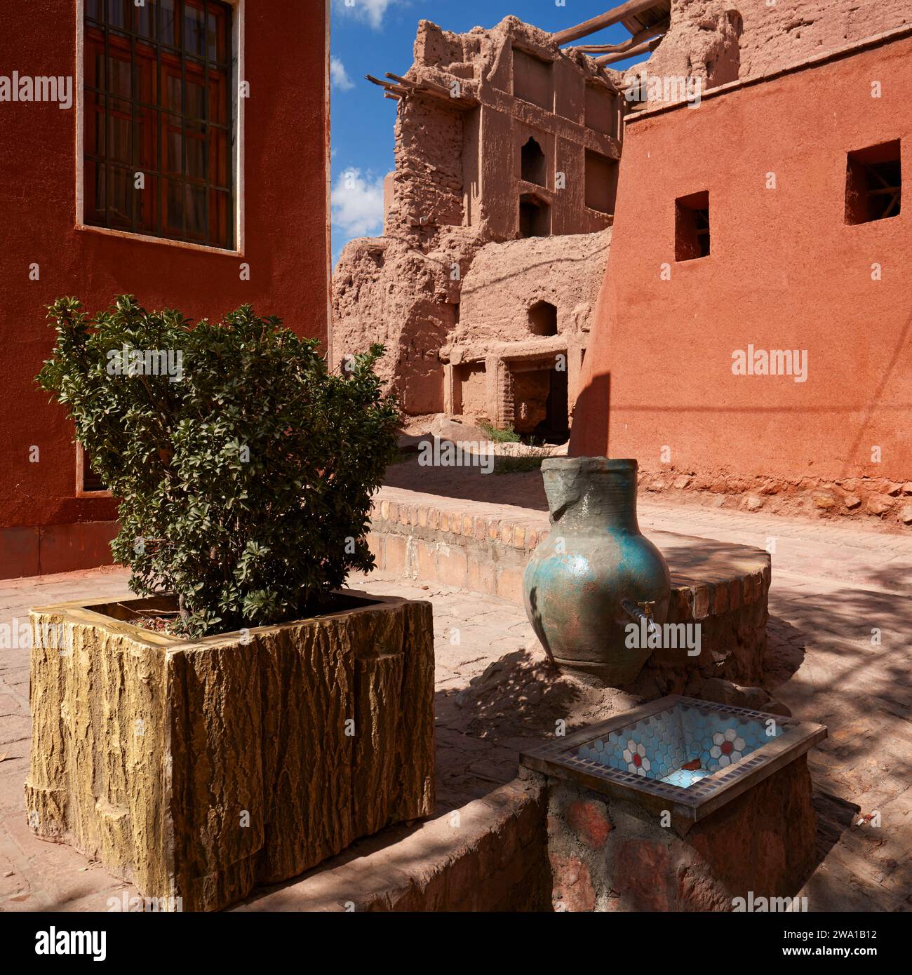 Potted houseplant and large water jug in front of a traditional house ...