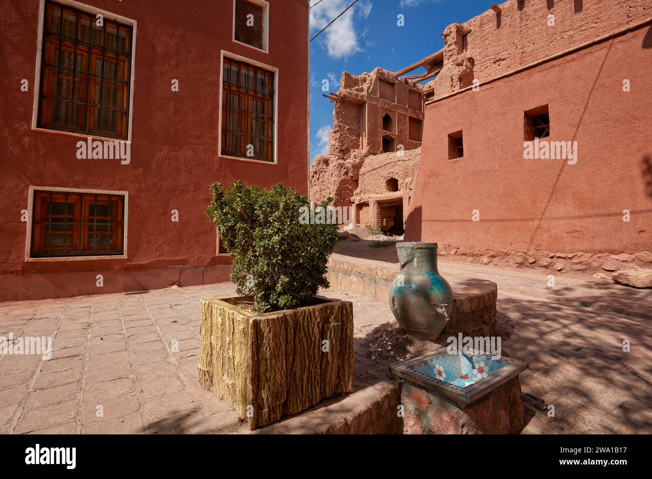 Potted houseplant and large water jug in front of a traditional house ...