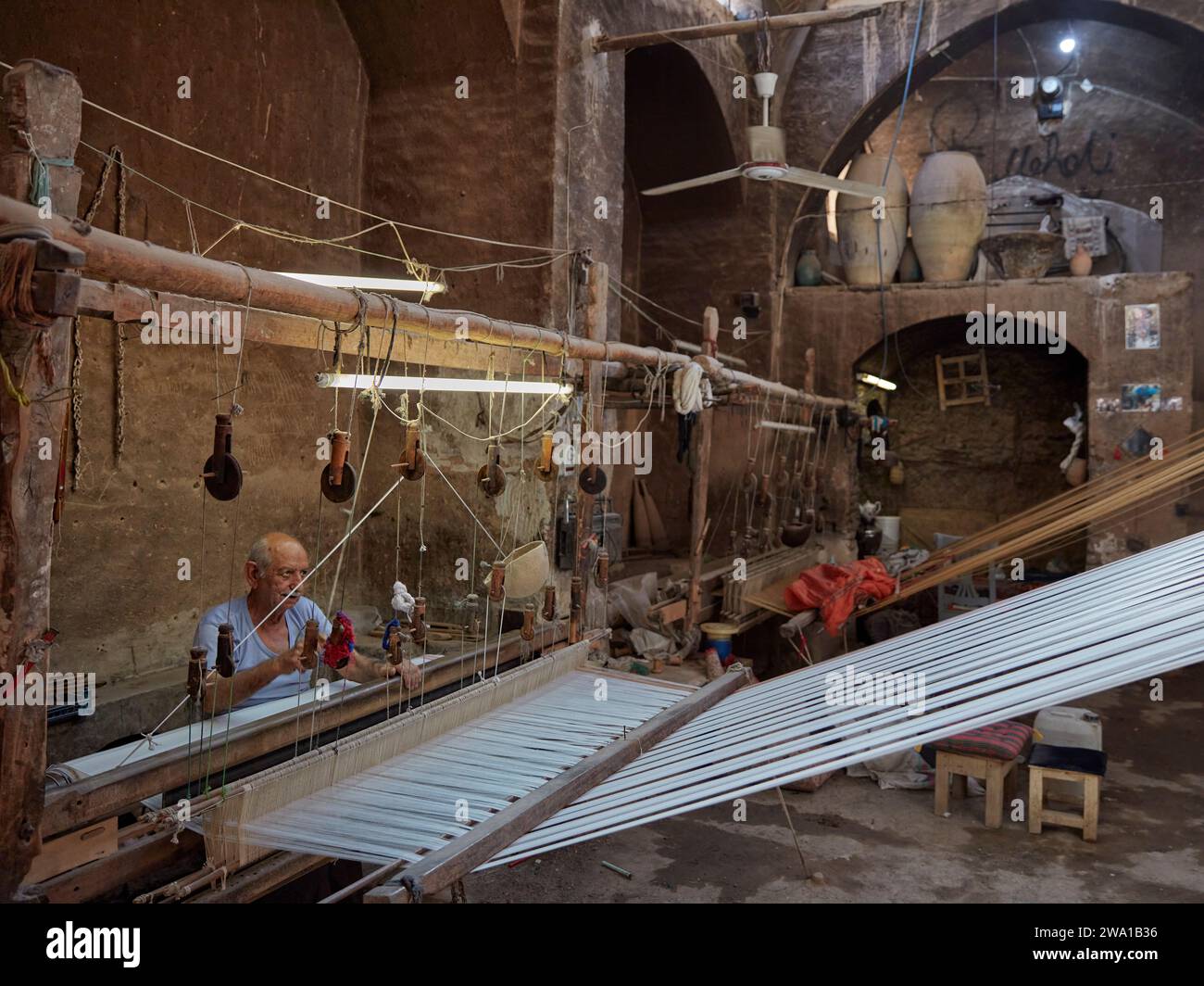 An older man works on horizontal loom in weaving workshop. Kashan, Iran ...