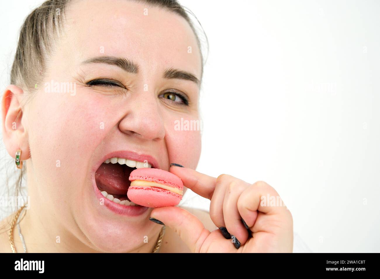 satisfied and happy woman eating macaroons on white background space ...