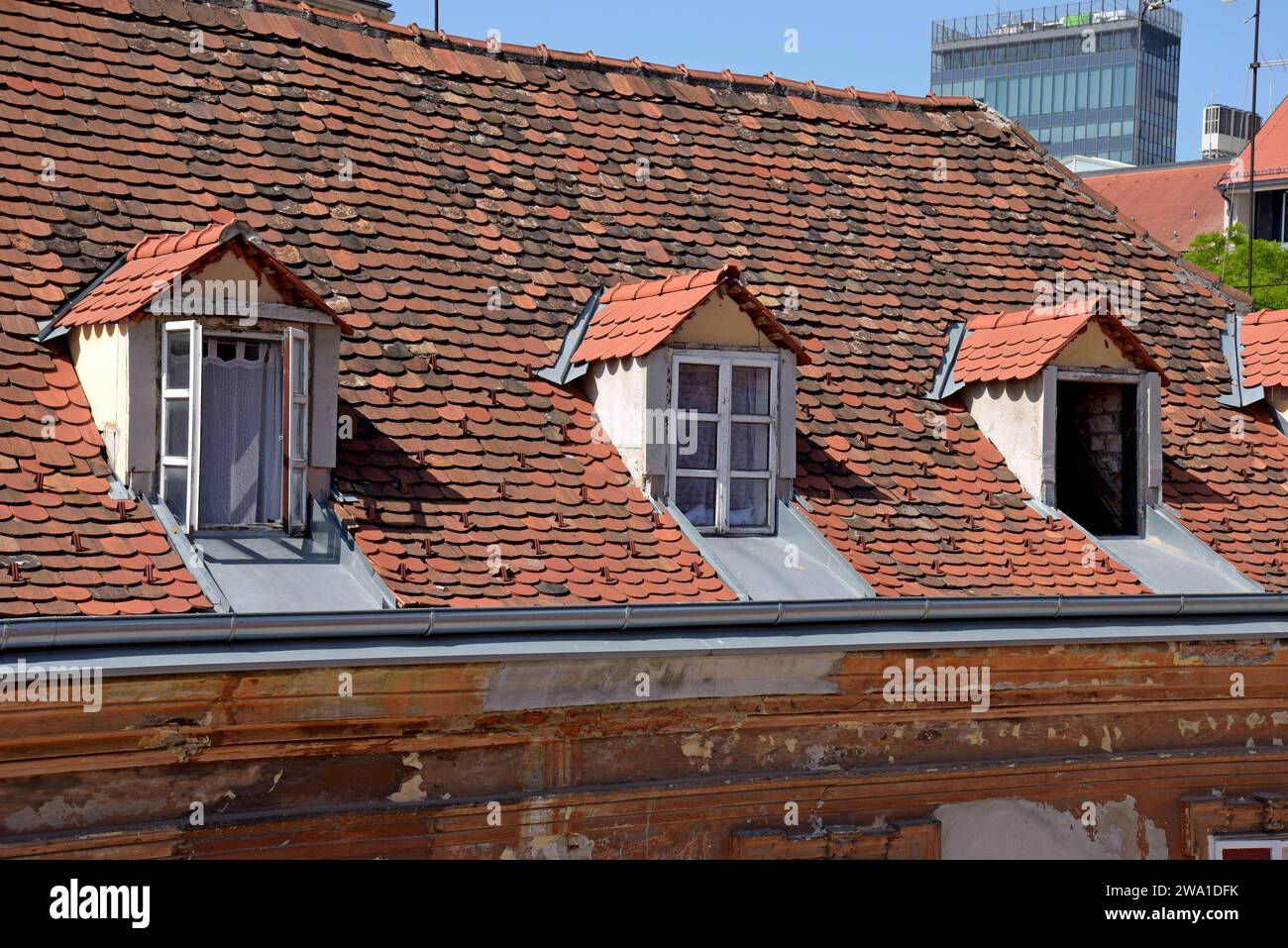 A run down roof with red tiles and dormer windows in the old town area ...