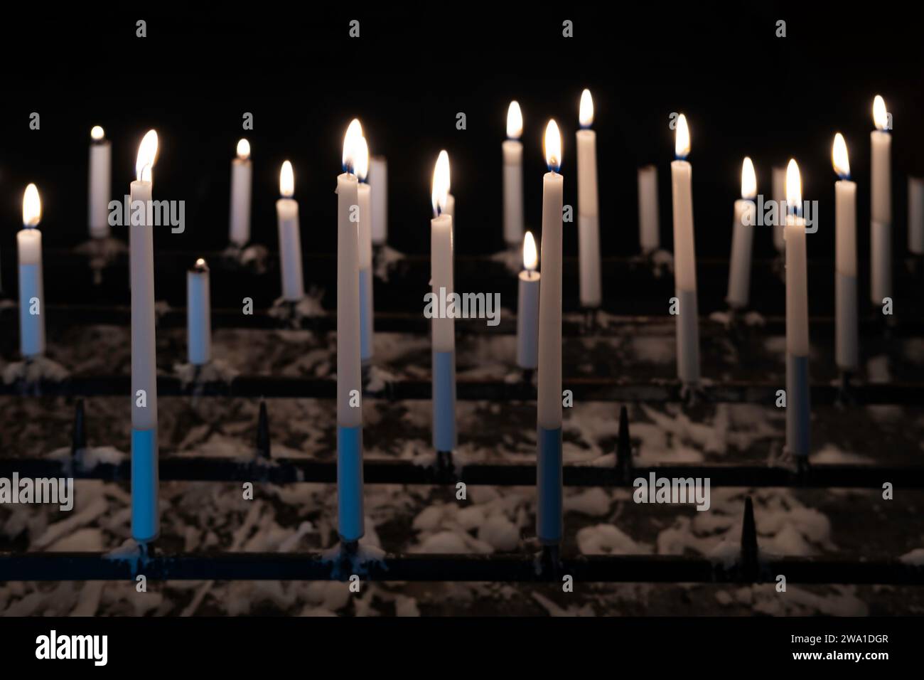 Row of candles with solidified wax underneath burn in a church or ...