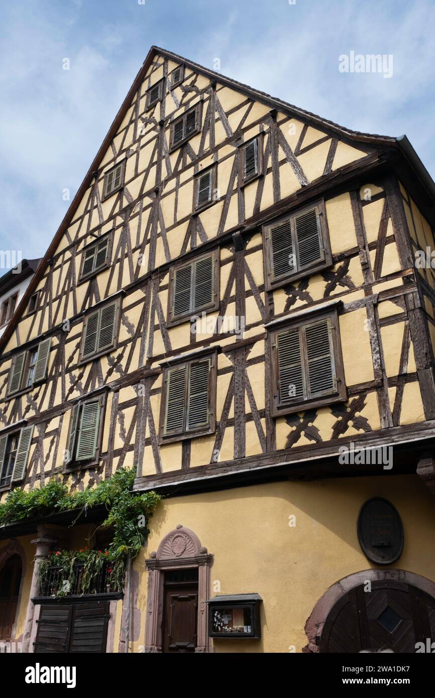 Facade of a colorful traditional half-timbered yellow house, named 'Le ...