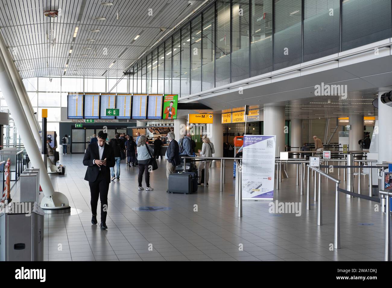 Travelers wait to check in in the hall at Schiphol Airport in Amsterdam ...