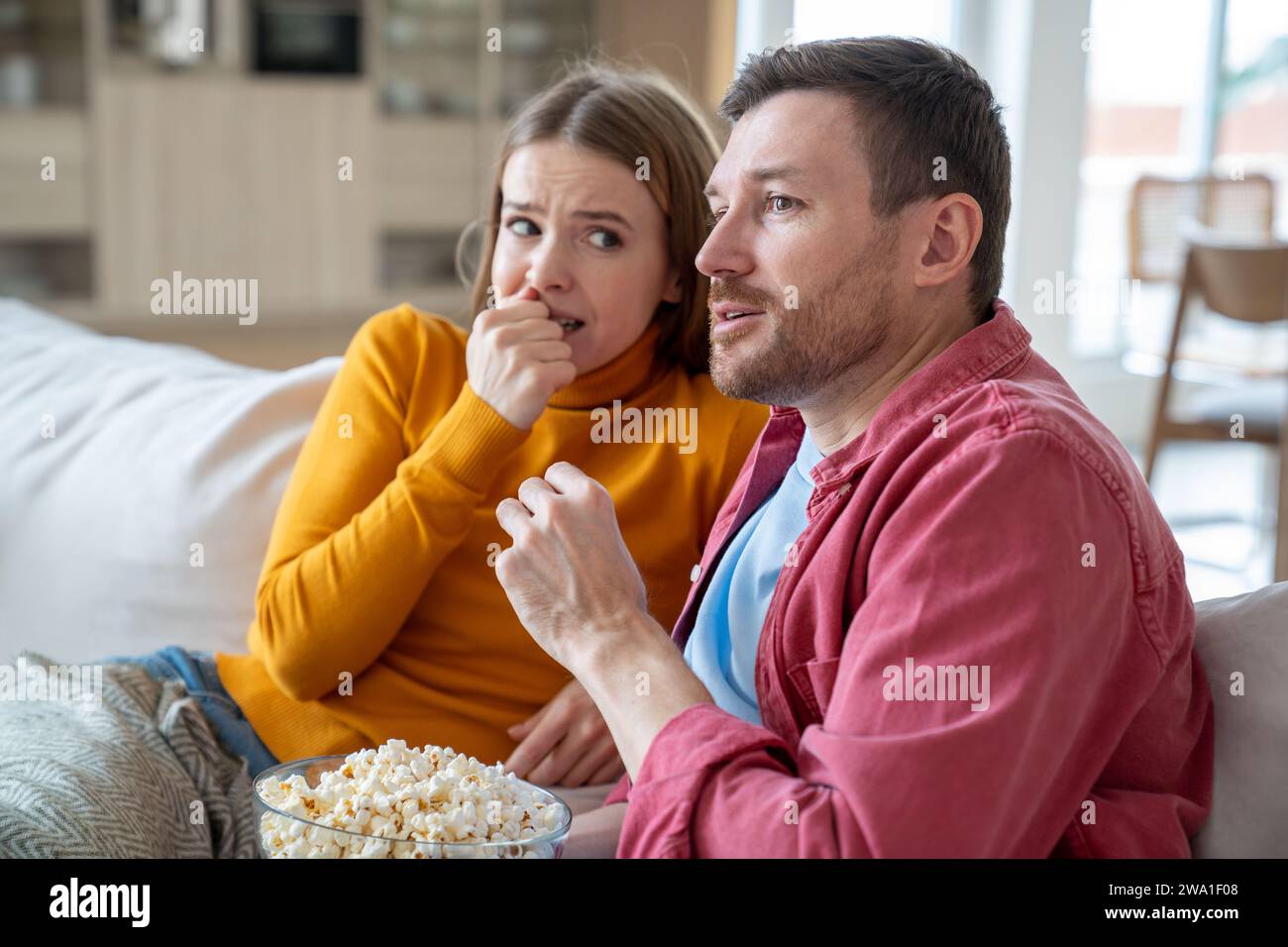 Emotional woman and intrigued man watching thriller, action film, scary ...
