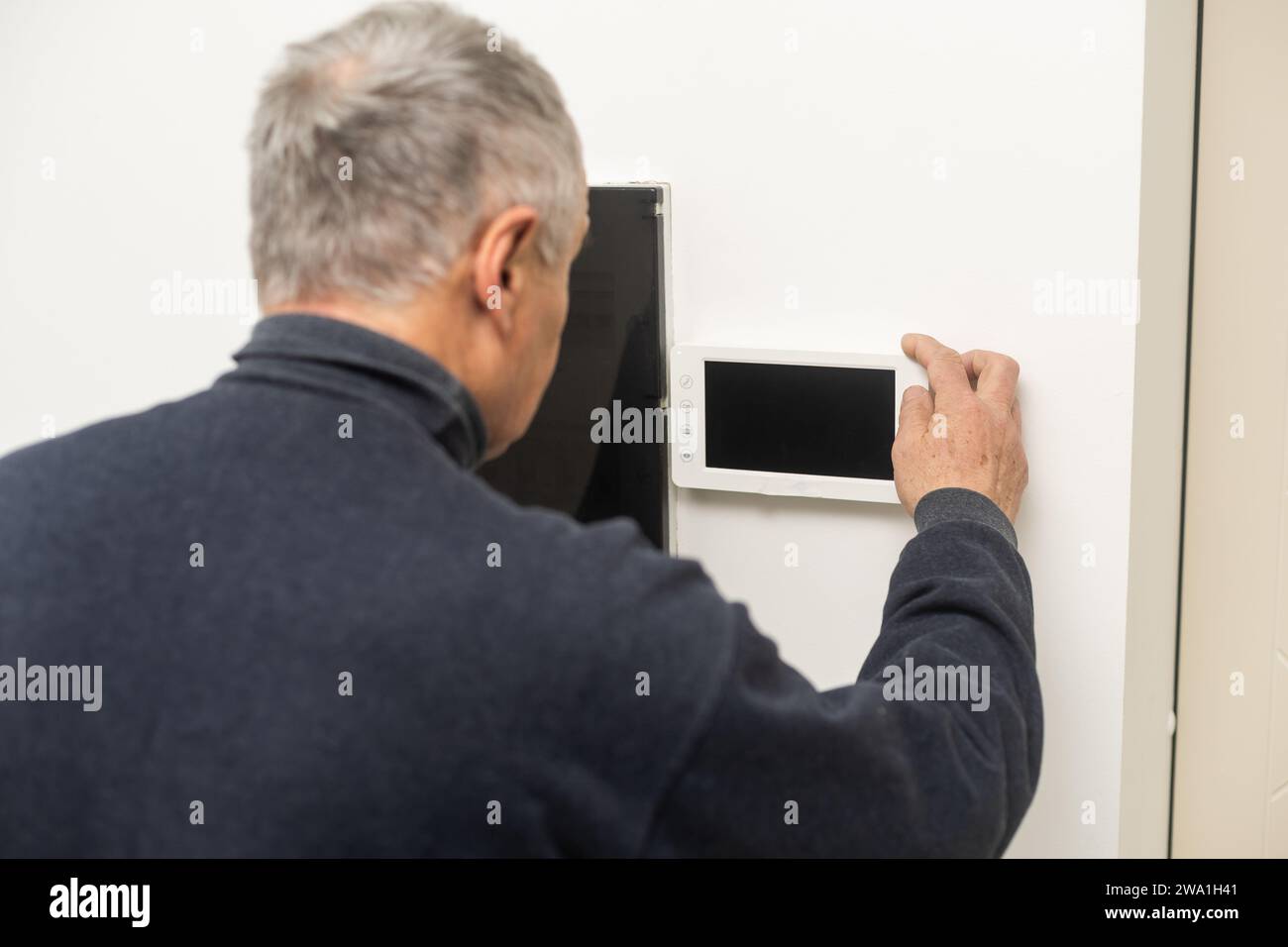 Older man repairing intercom system Stock Photo - Alamy