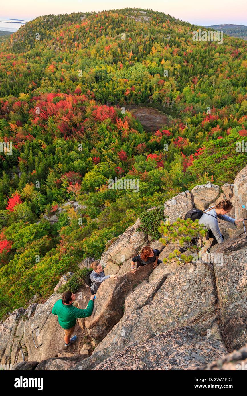 Side view of people climbing Beehive in fall in Acadia National Park ...