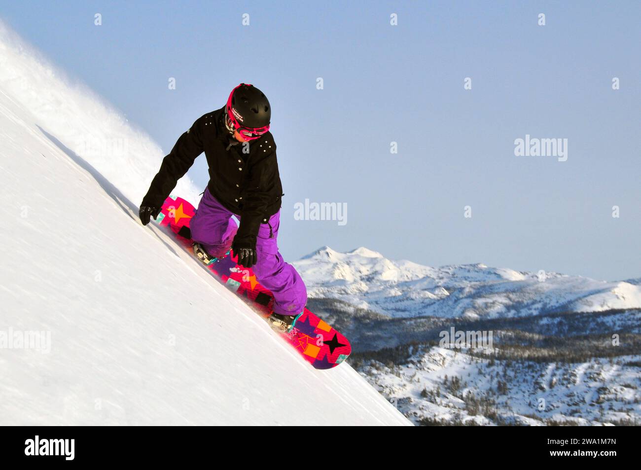 A woman snowboarding on a steep pitch at a mountain resort near South ...