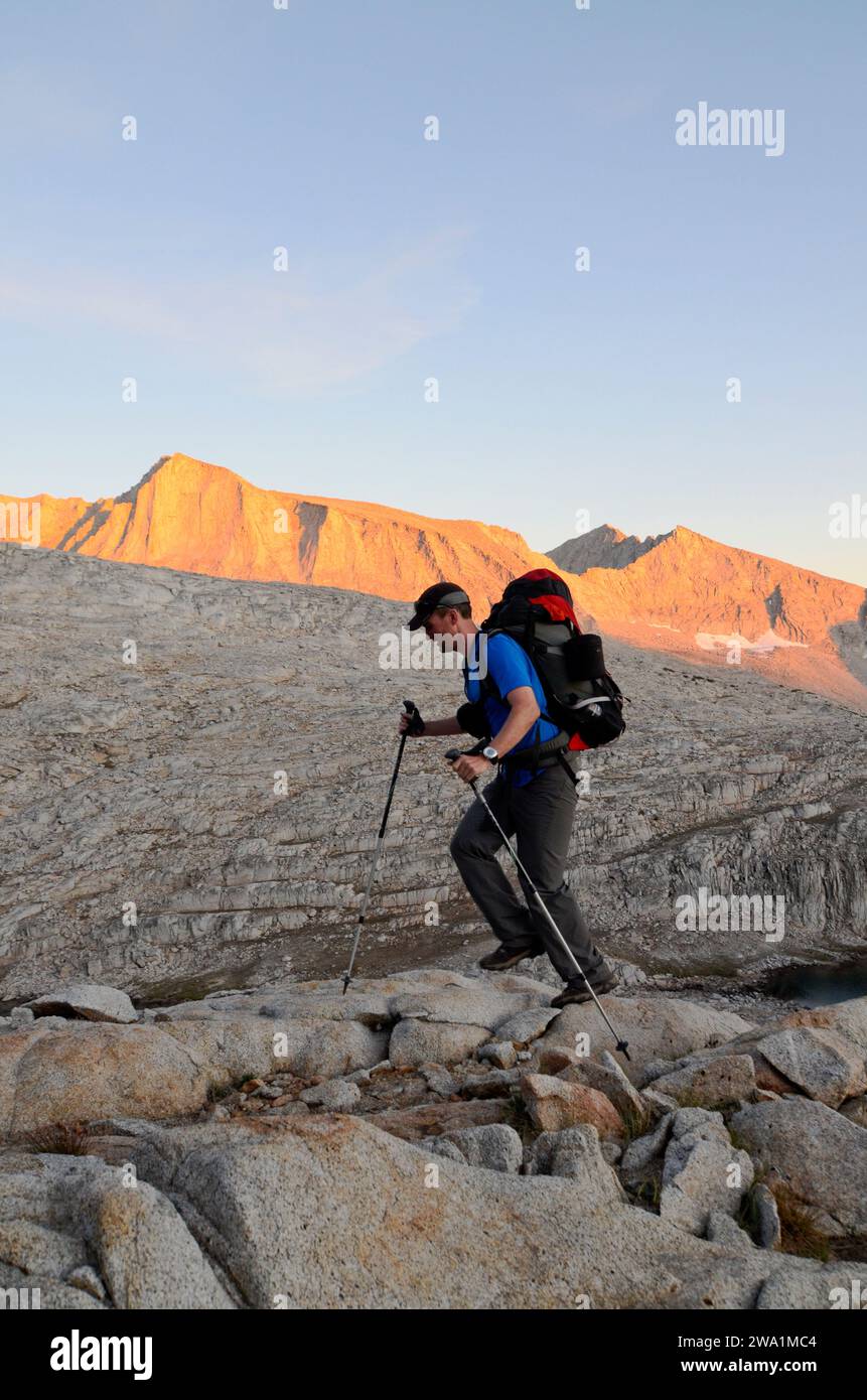 A backpacker hikes towards Frozen Lake Pass with alpine glow on the ...